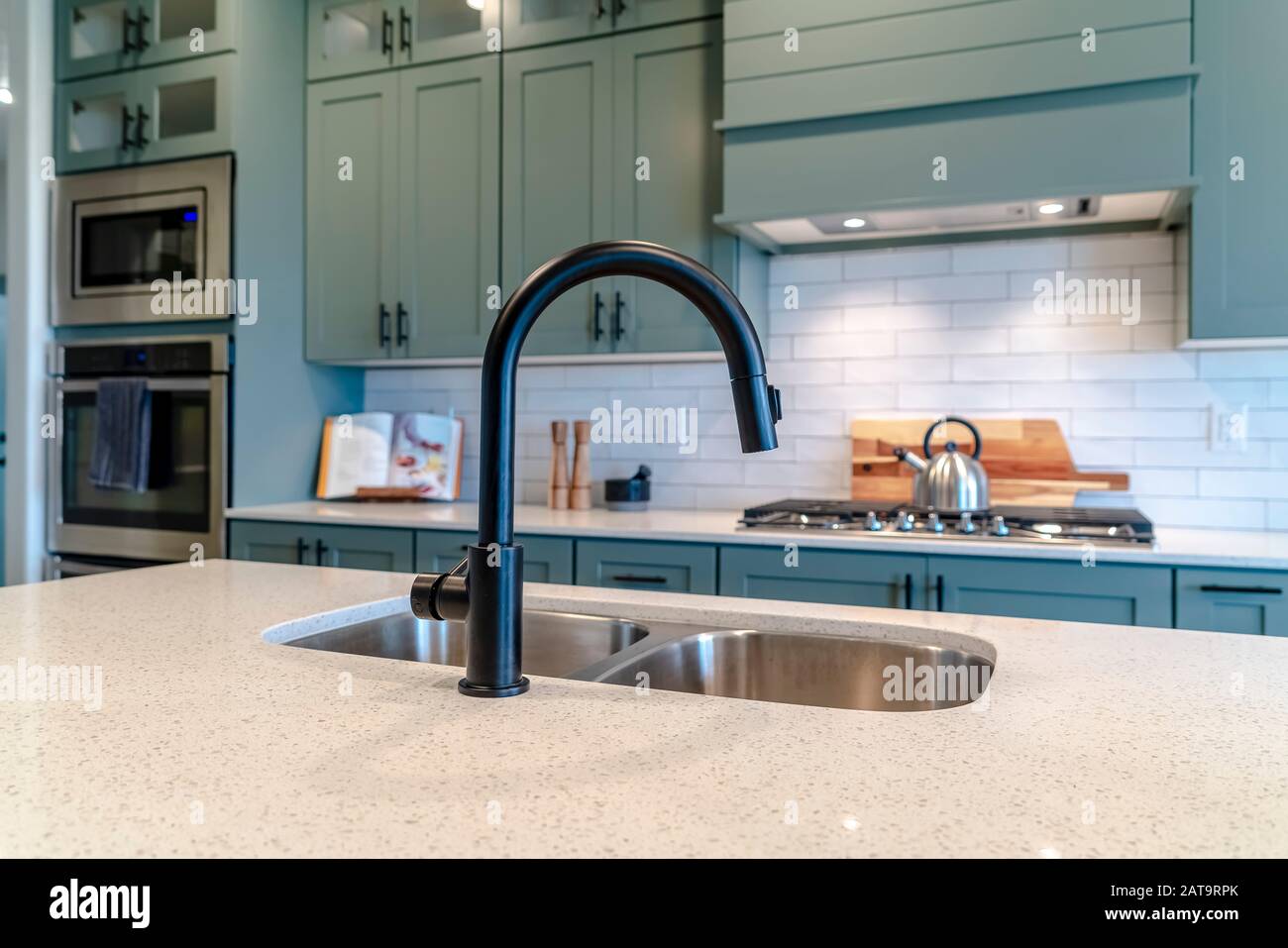 Kitchen island sink with black faucet against cooking appliances and ...