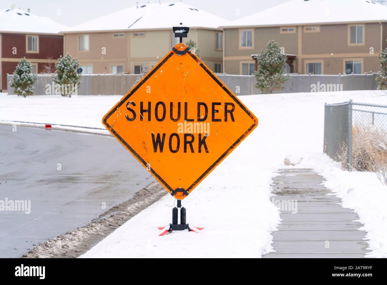 Shoulder Work sign on the snowy sidewalk of road under construction in ...