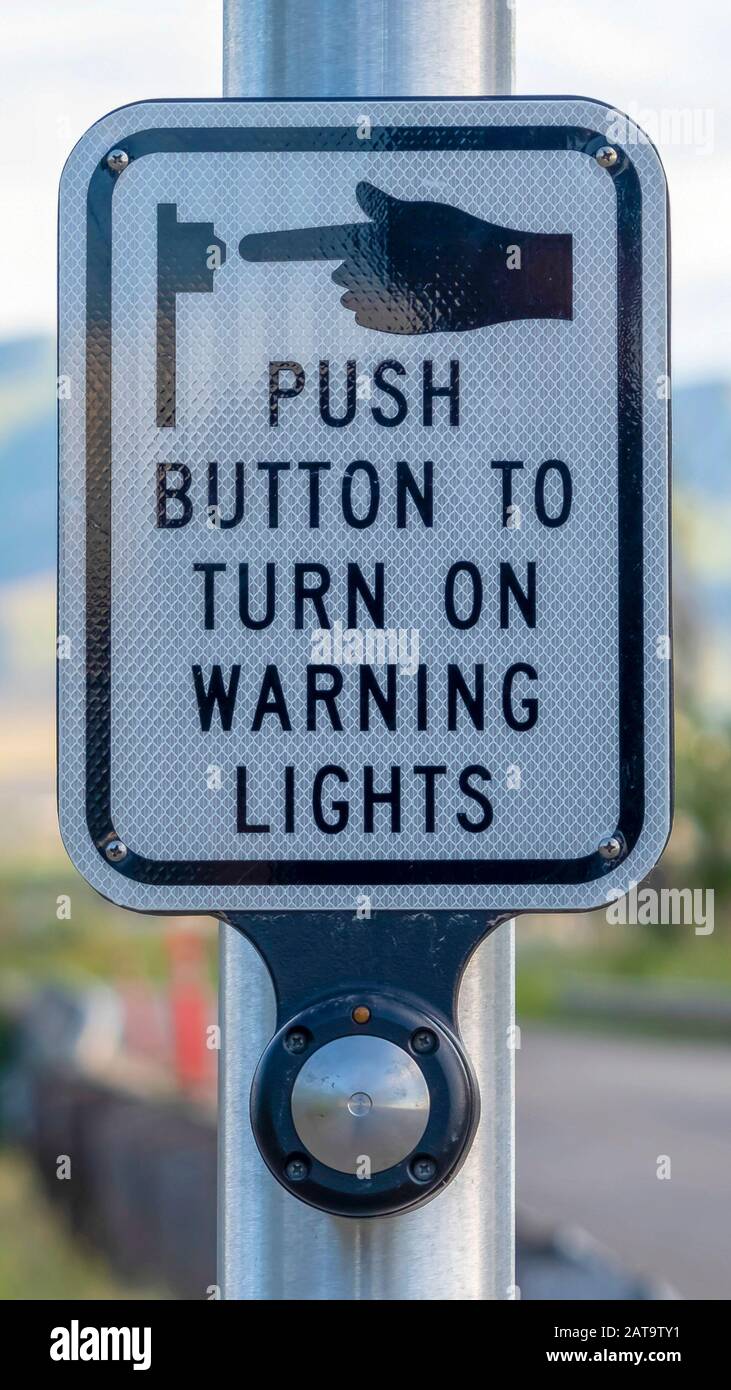 Vertical Pedestrian push button station at a crosswalk against blurred ...