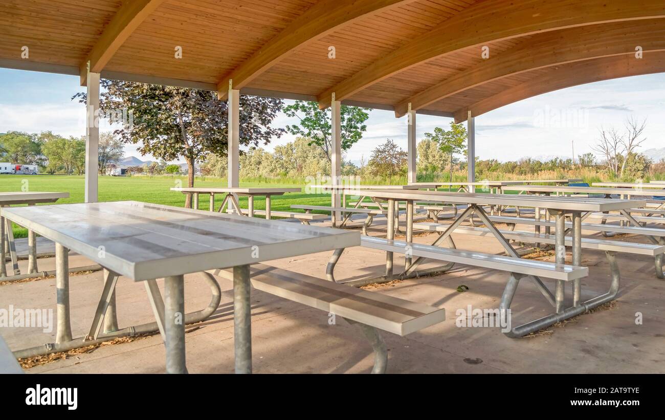 Panorama frame Eating area at a park with tables and seats under brown ...