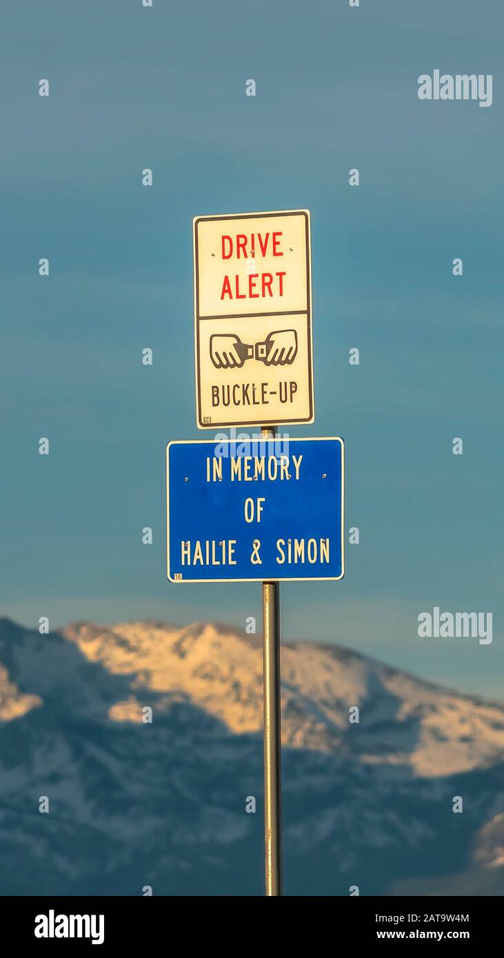 Vertical Drive Alert and Buckle Up road sign against snowy mountain and ...
