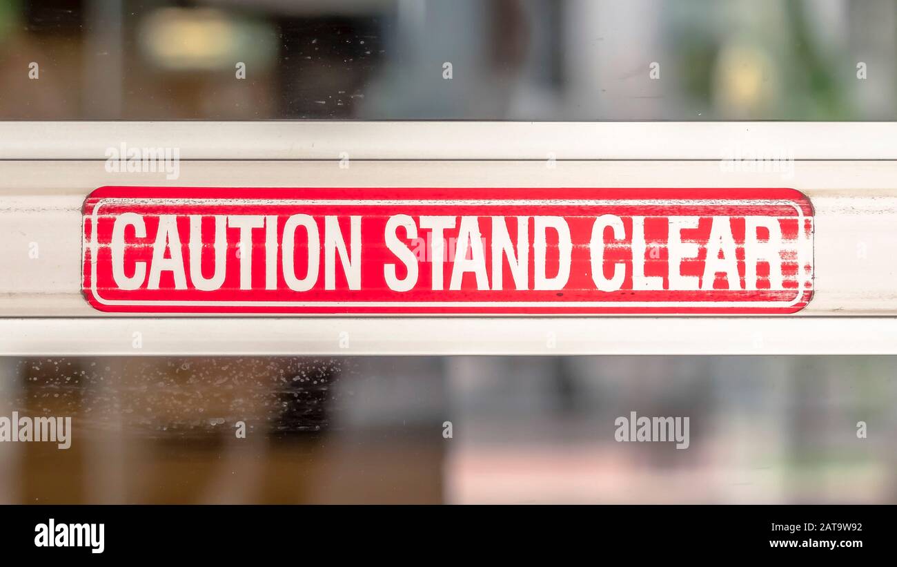 Panorama Caution Stand Clear sign on the metal plate of the glass door ...