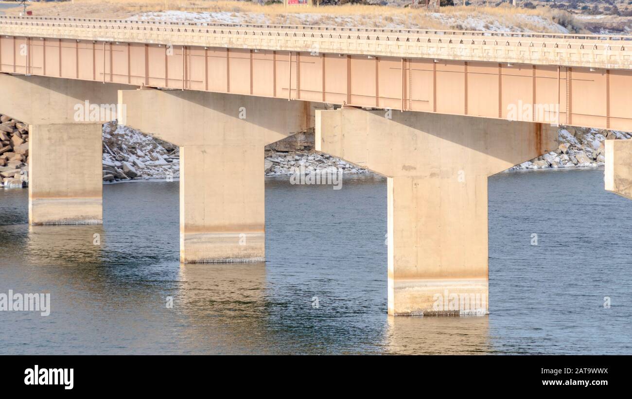 Panorama Massive bridge over shiny lake with grassy and snowy landscape ...