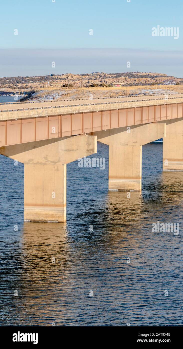 Vertical frame Stringer bridge spanning over calm lake with view of ...