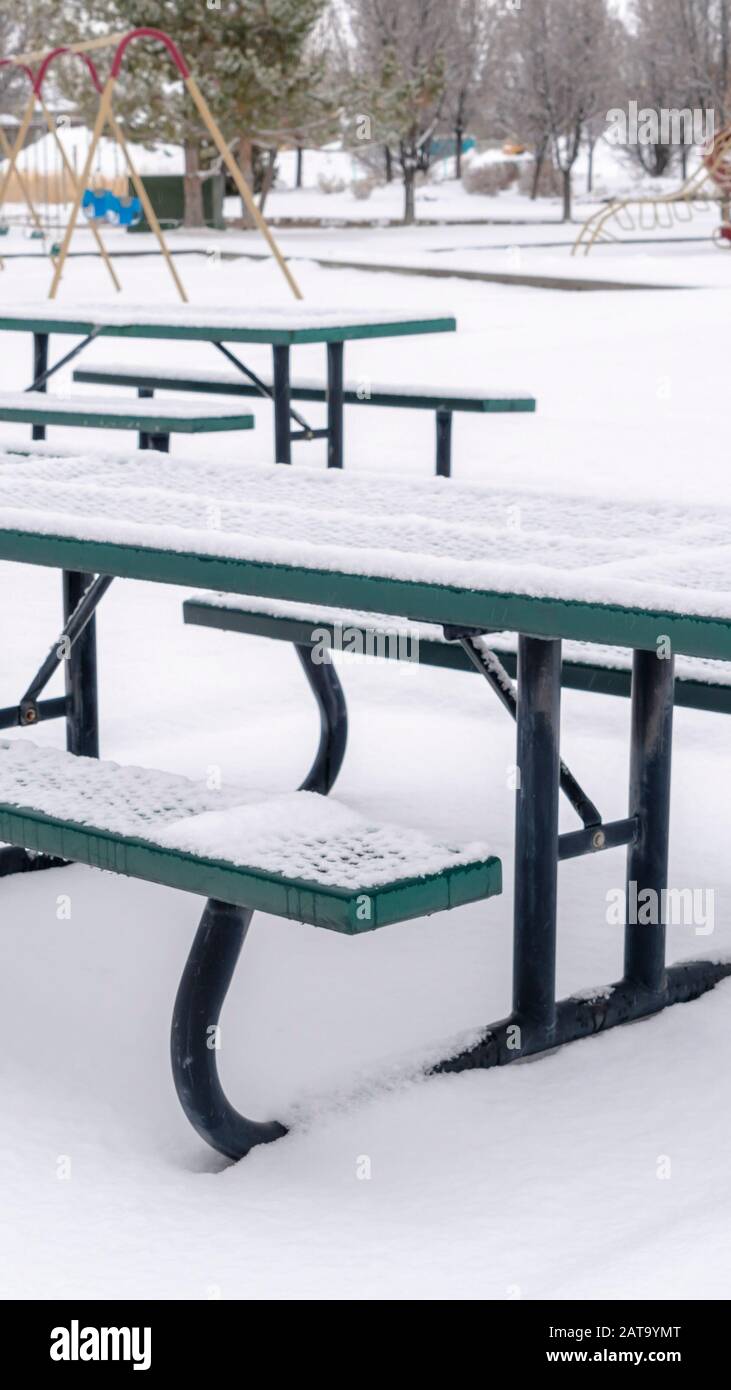 Photo Vertical frame Snowy picnic tables and benches at a park ...
