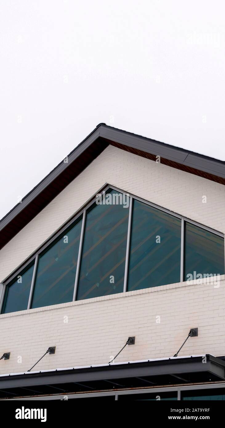 Photo Vertical Home exterior with tringular window and white wall under ...