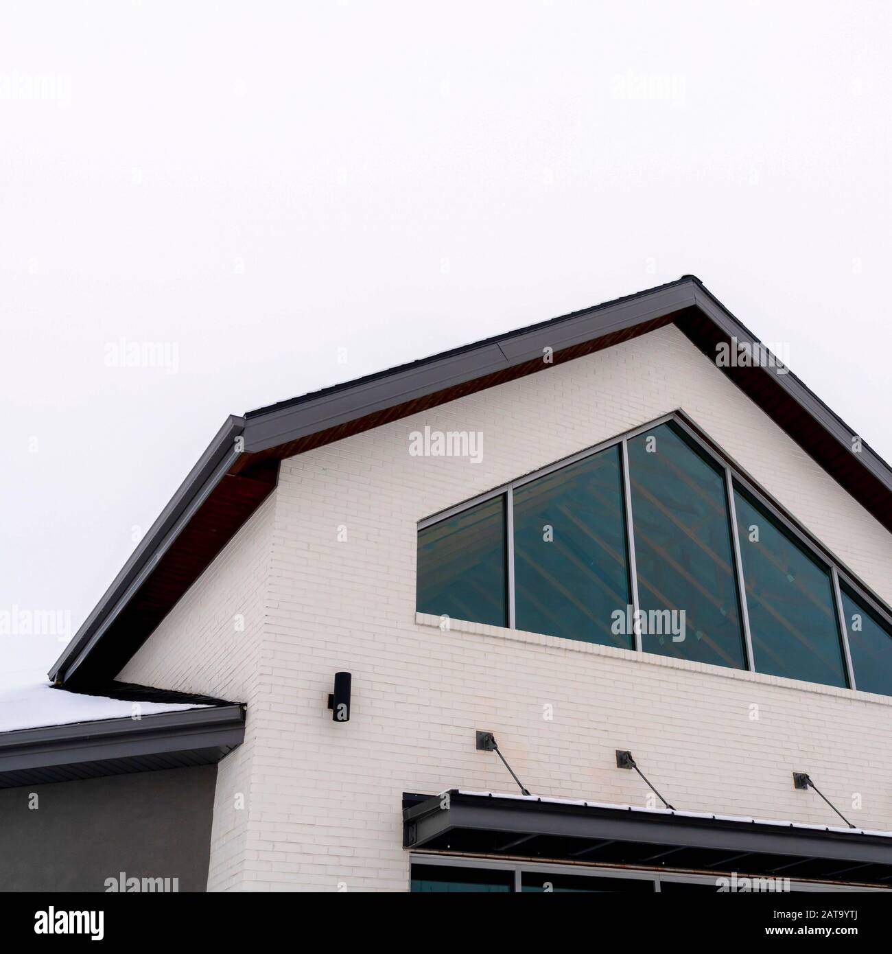 Square frame Home exterior with tringular window and white wall under ...