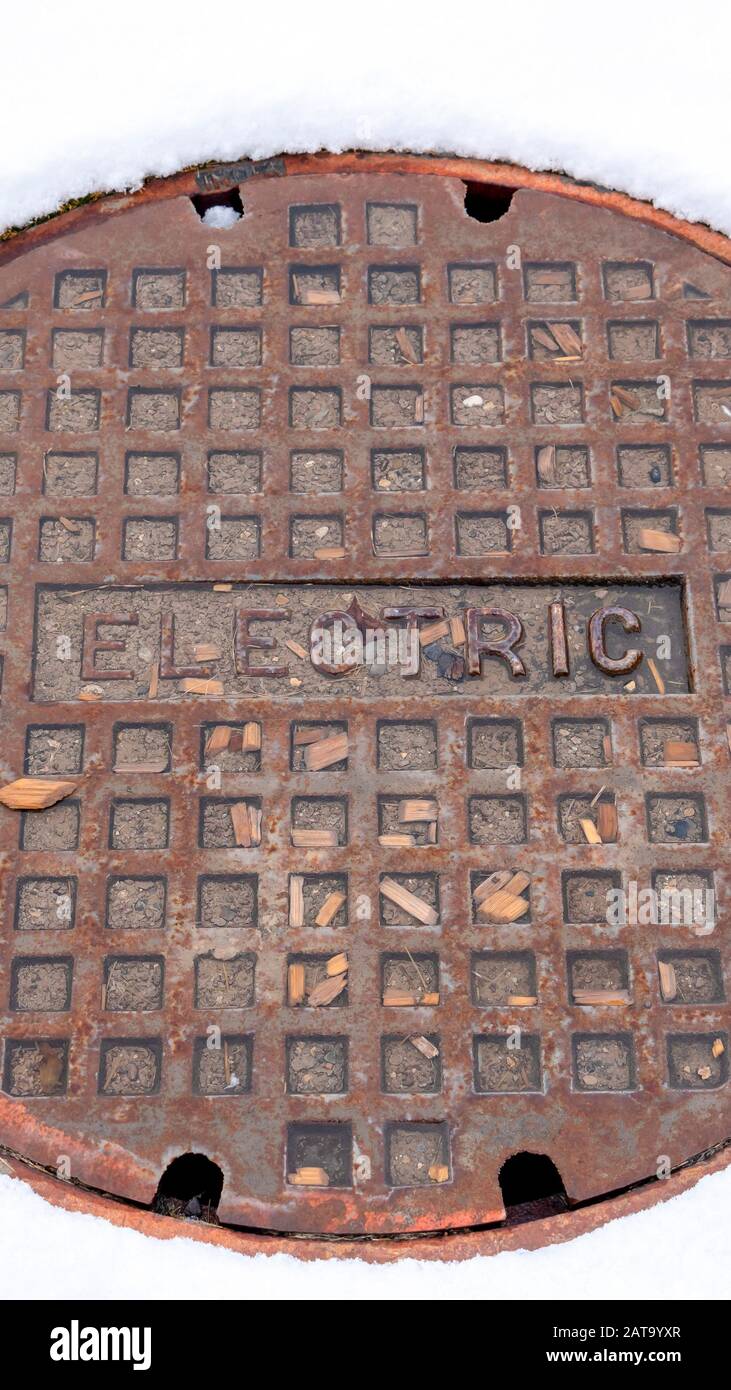 Vertical Rusty circular utility electric manhole cover amid fresh white ...
