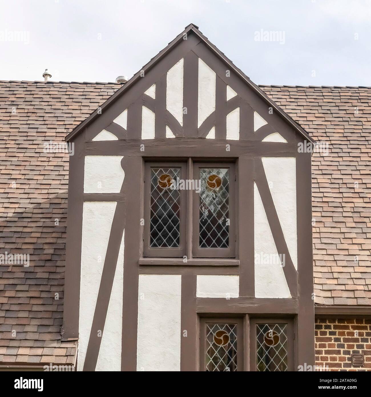 Square Gabled dormer with decorative windows against brick wall and ...