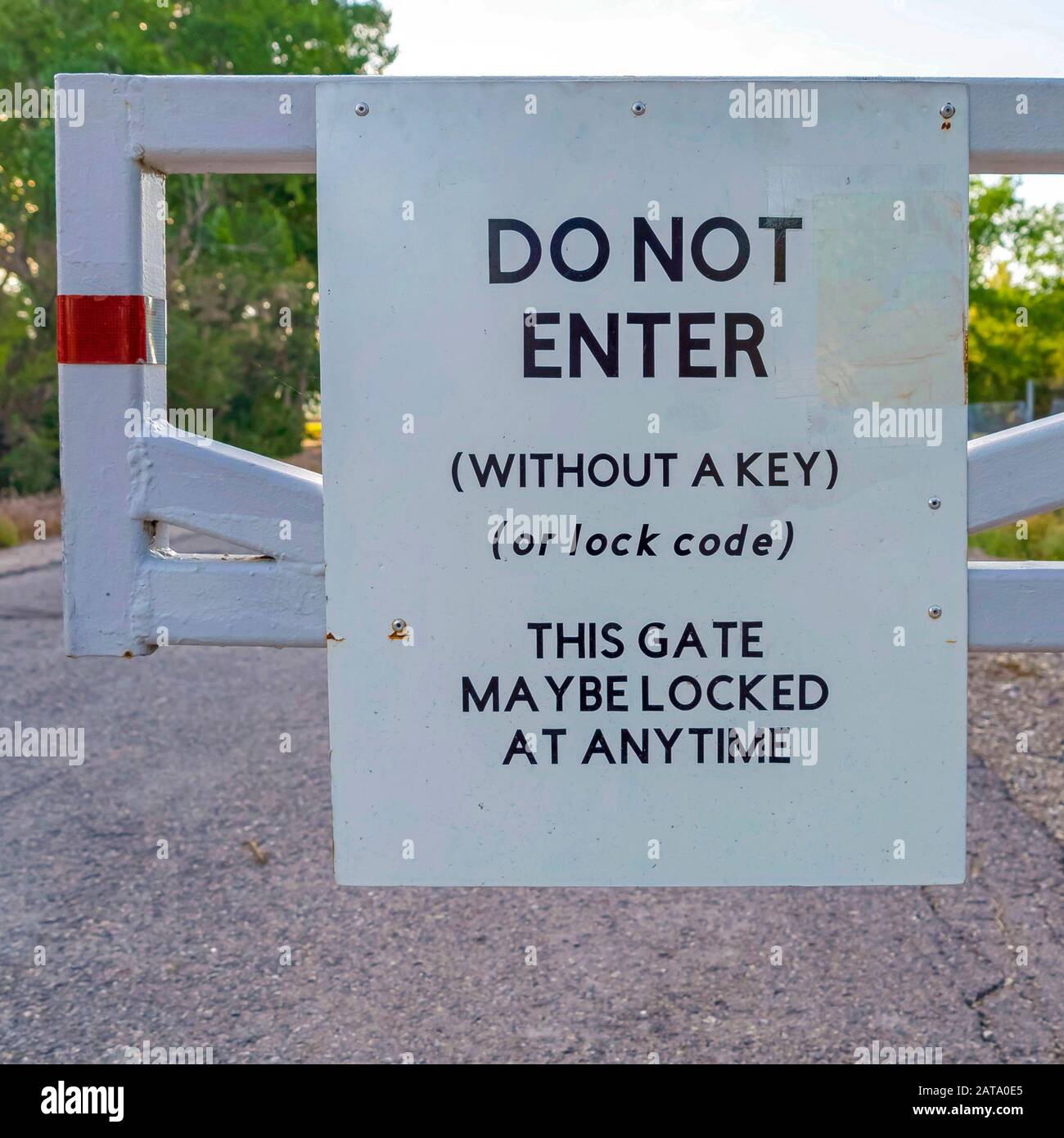 Square Do Not Enter sign mounted on a white gate against road trees and ...