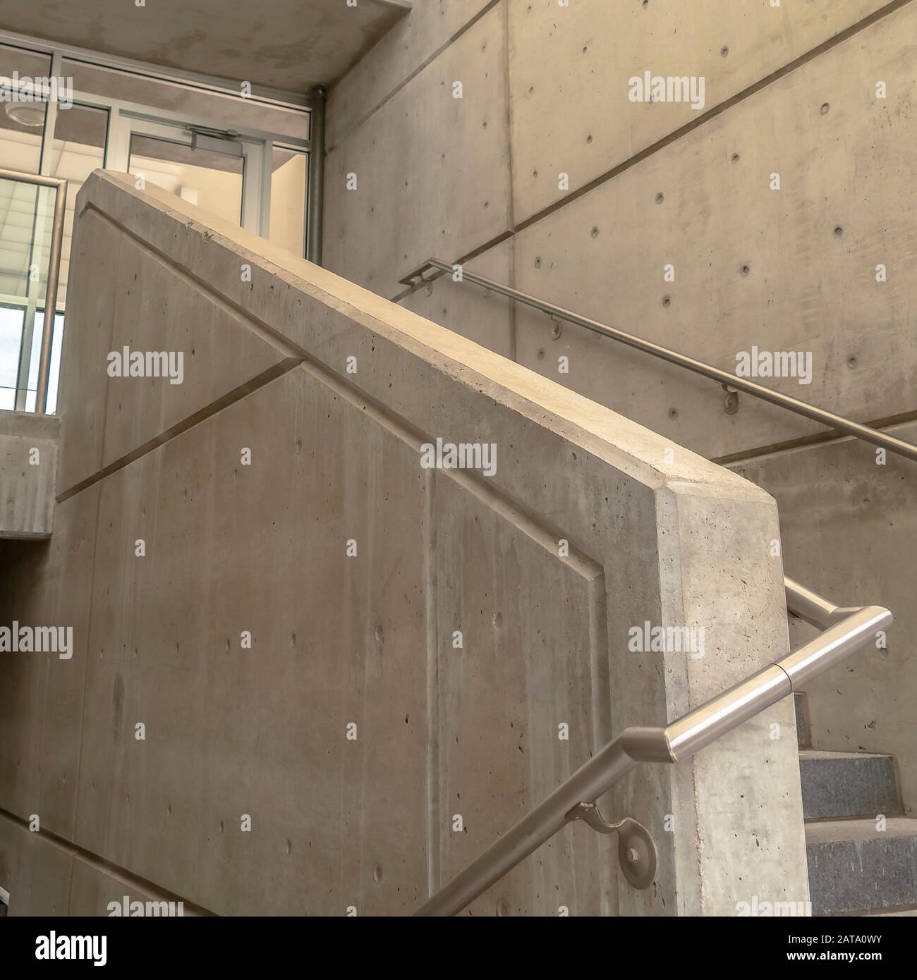 Square Building with slant glass roof over stairs leading to glass door ...