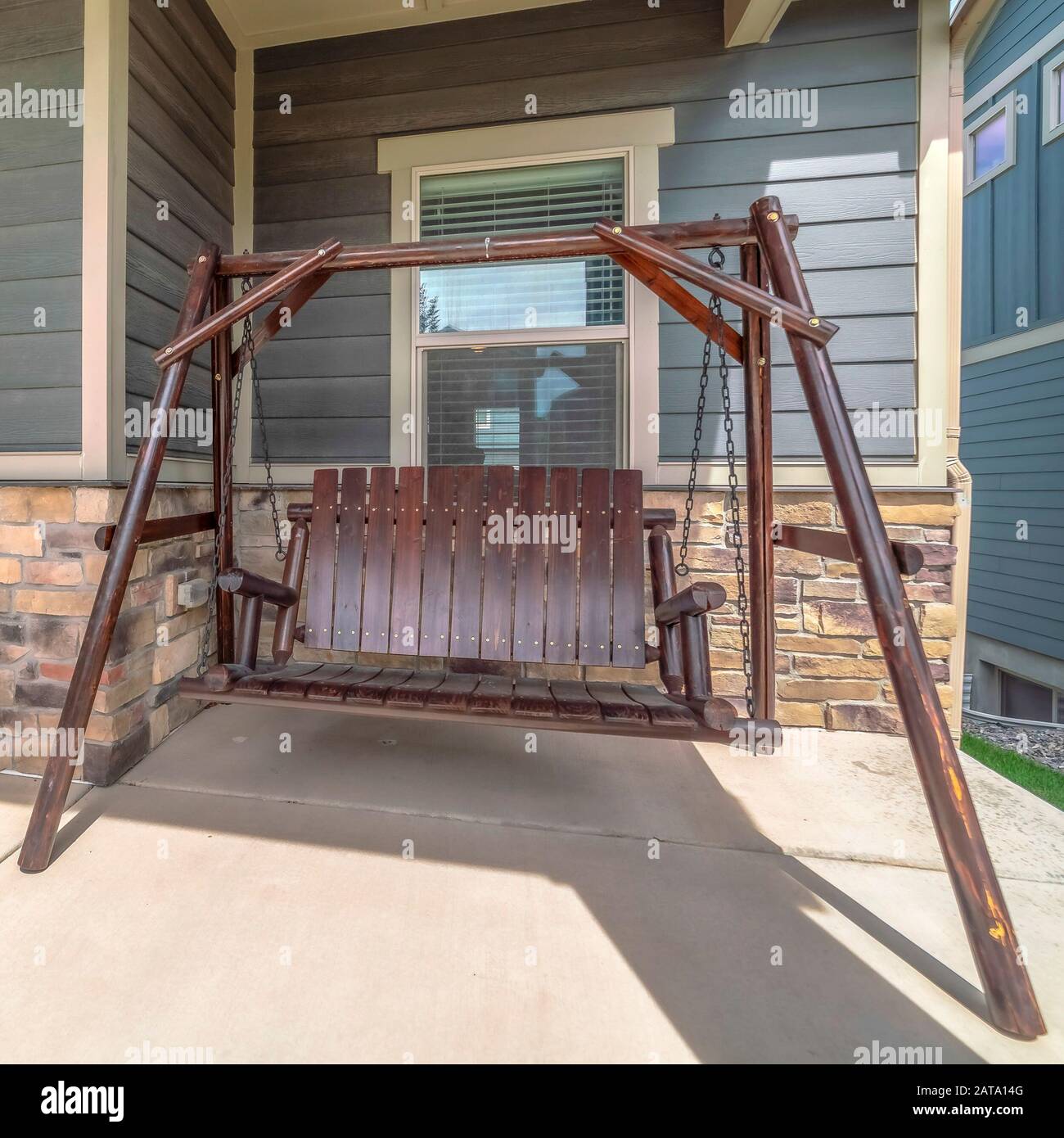 Square frame Brown wooden bench swing at the porch of a home with ...