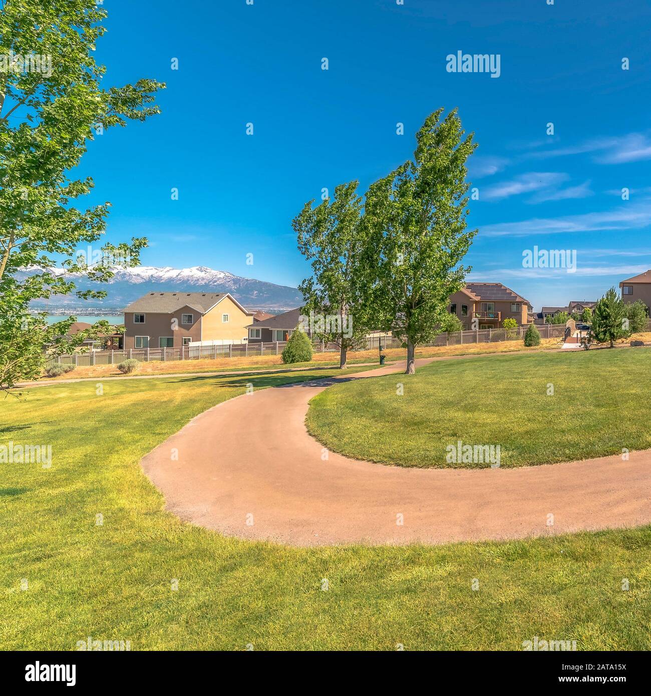 Square Pathway curving through vast grassy field with homes lake and ...
