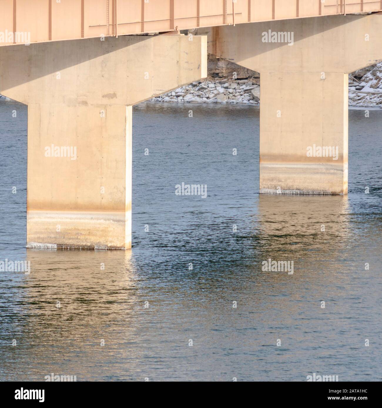 Square frame Massive bridge over shiny lake with grassy and snowy ...
