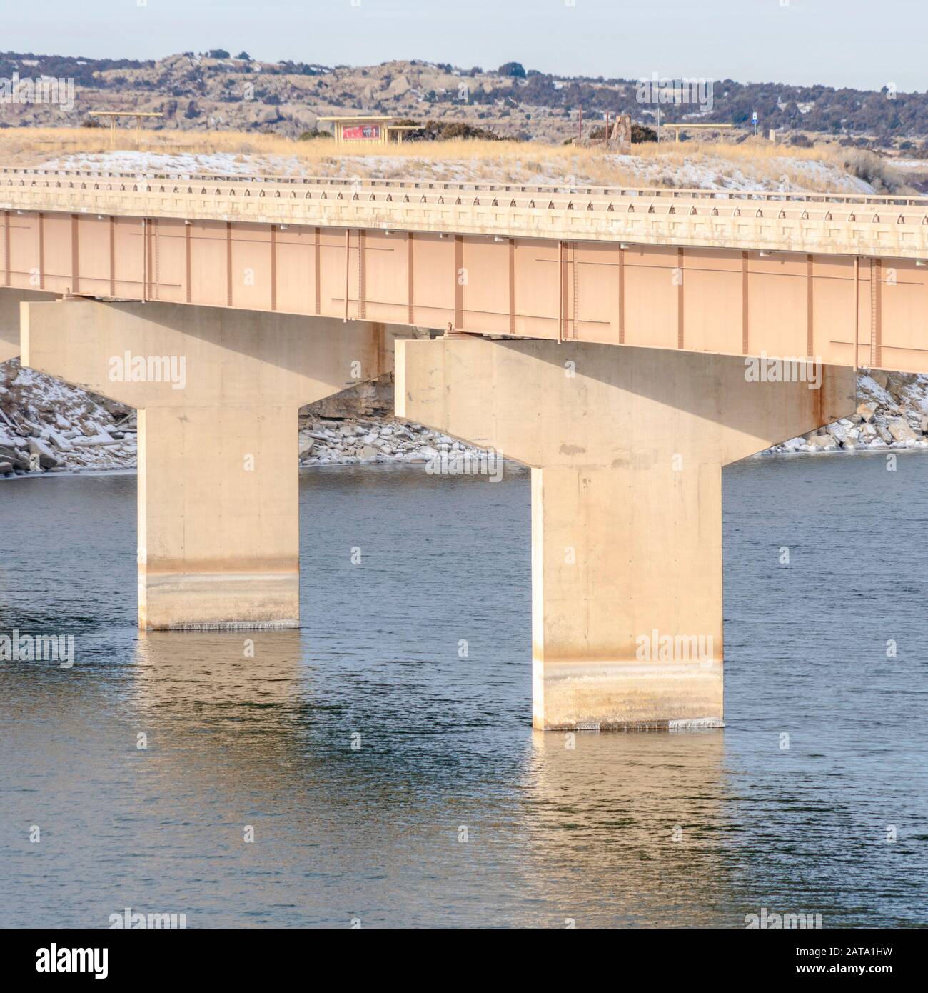 Square Massive bridge over shiny lake with grassy and snowy landscape ...