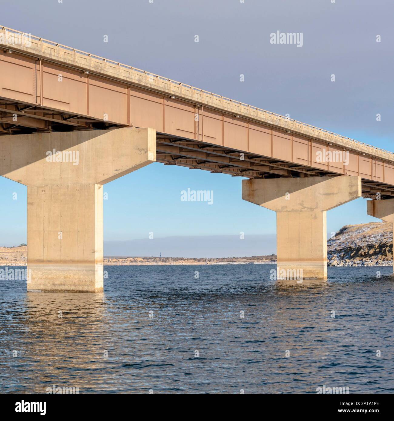 Square frame Stringer bridge spanning over a lake with view of snowy ...