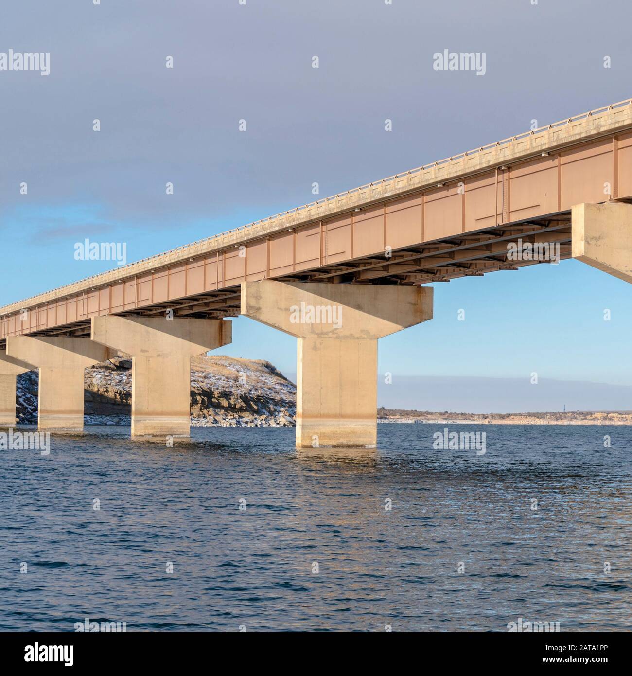 Square Stringer bridge spanning over a lake with view of snowy terrain ...
