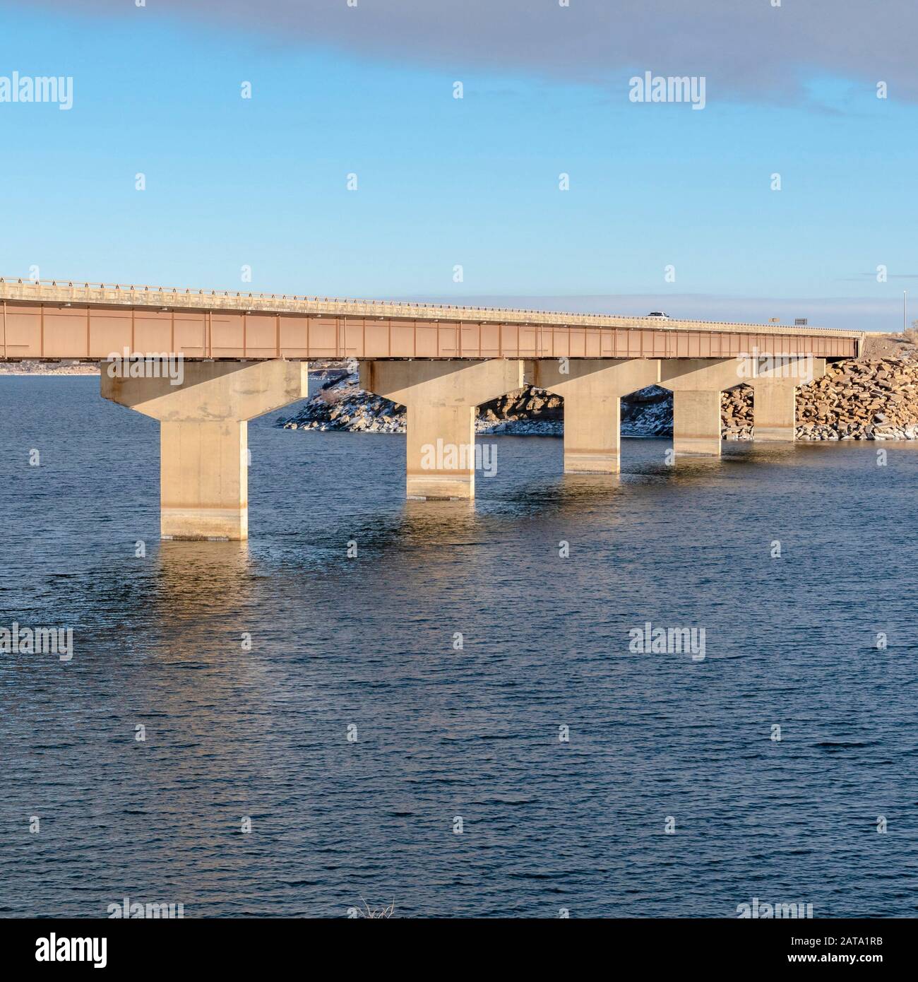 Square Bridge across blue lake with views of snow covered hills and ...