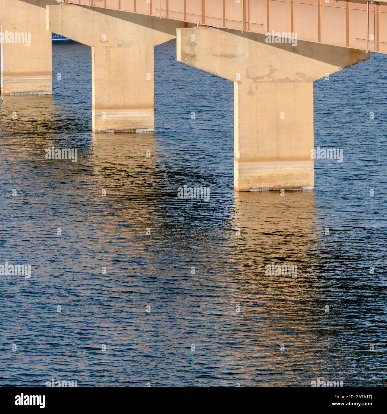 Square frame Stringer bridge spanning over calm lake with view of snowy ...
