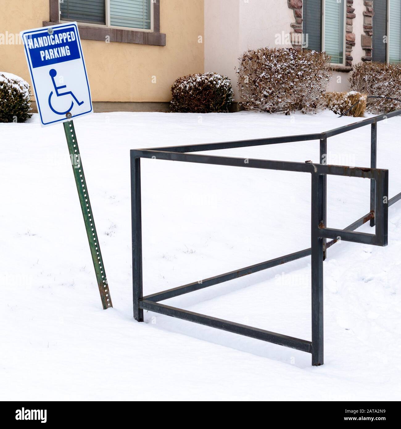 Square Handicapped Parking sign and wheelchair ramp at a snowy parking ...