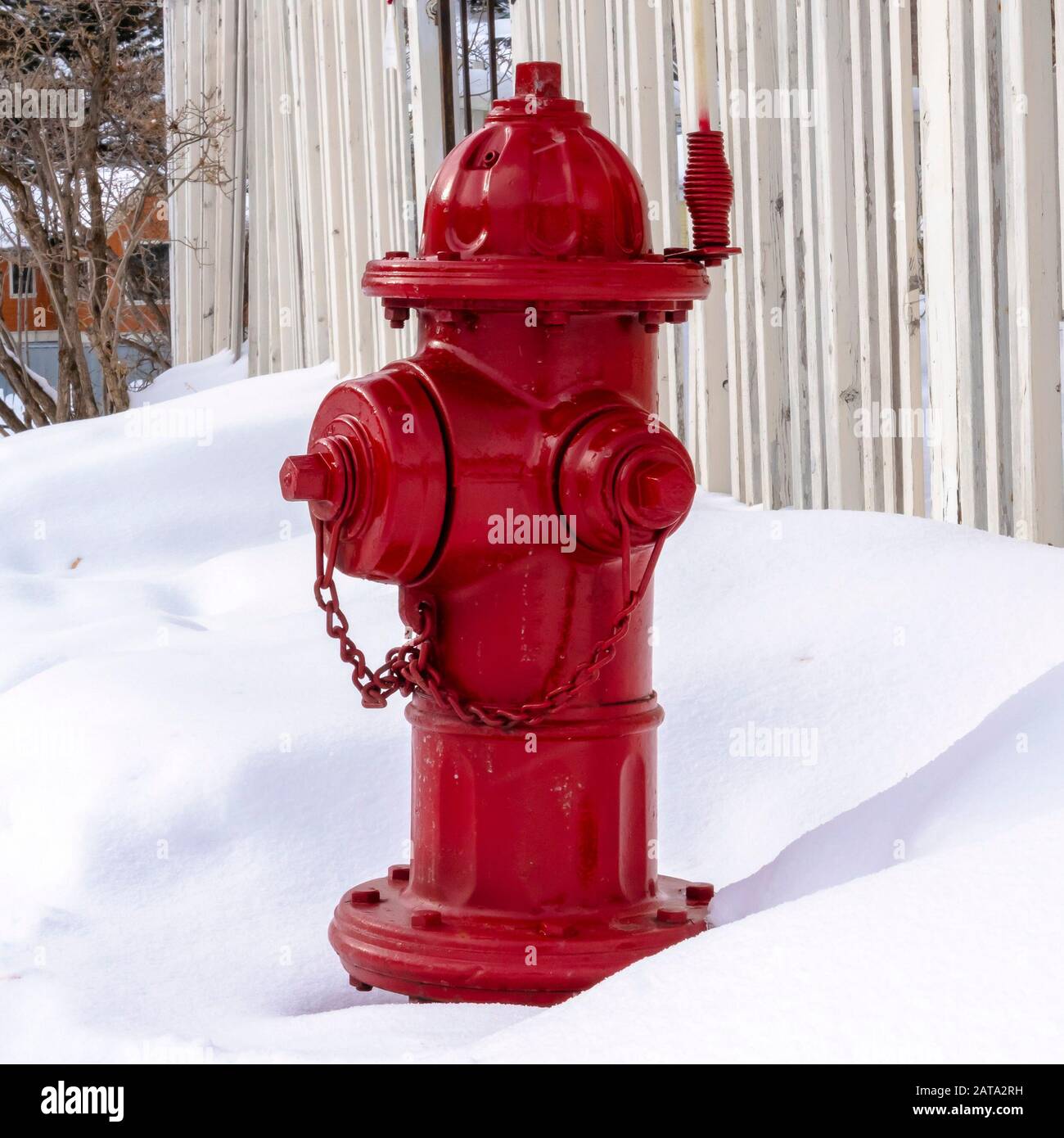 Square frame Vibrant red fire hydrant against snow and hill homes at ...