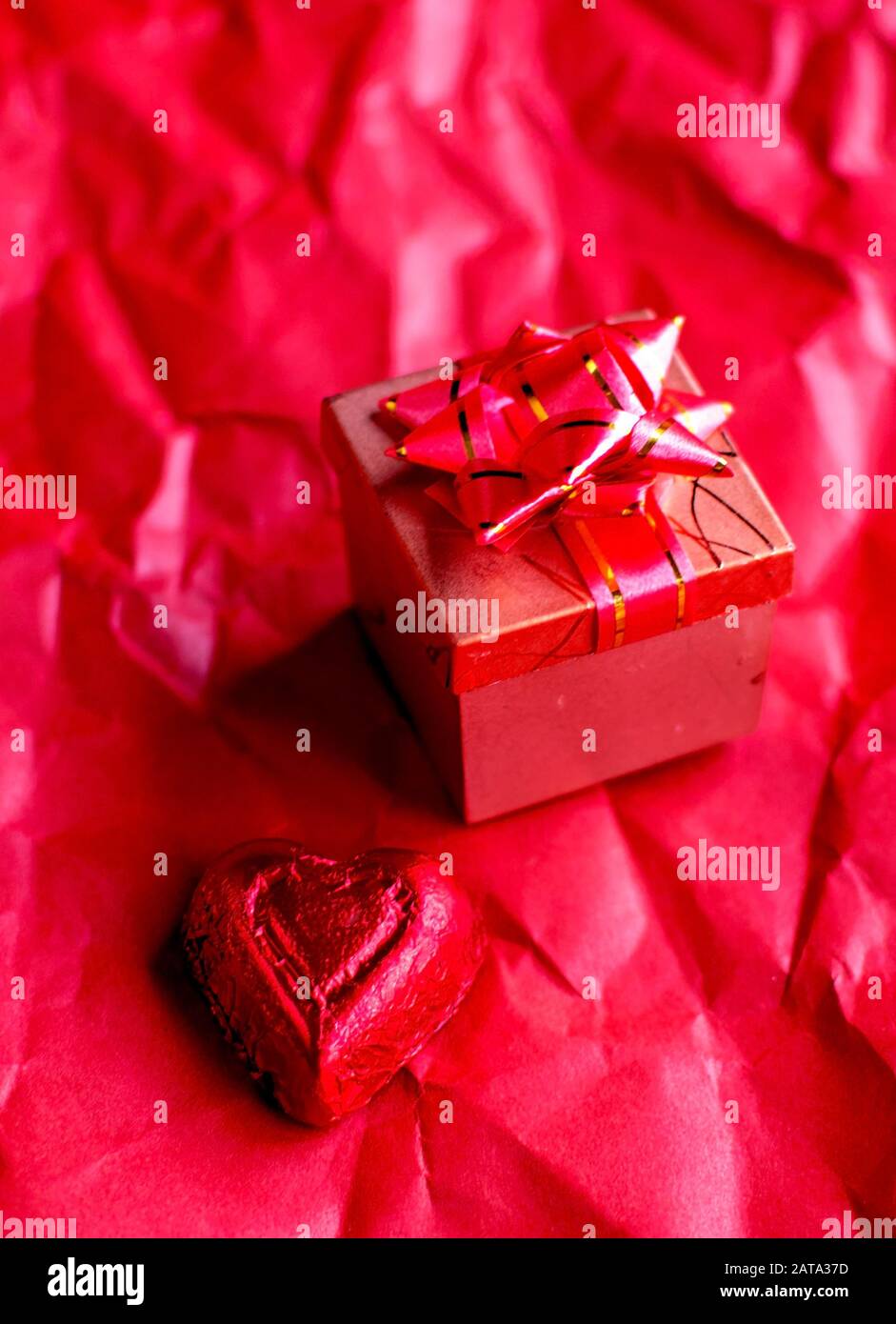 small gift box with a ring inside, and a red foil wrapped chocolate ...