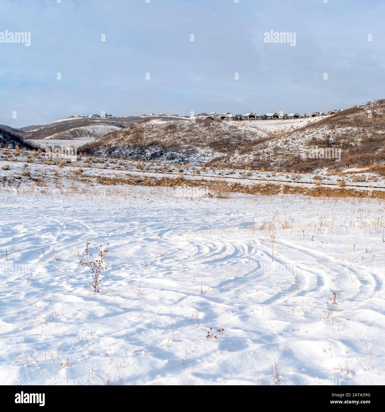 Square Field with snow in winter with homes on snowy hill against sky ...
