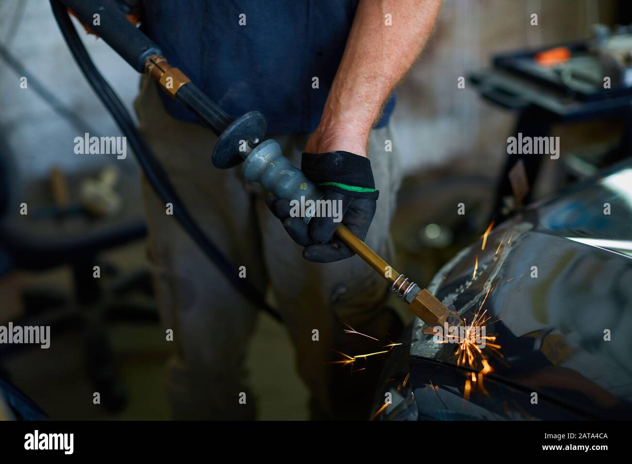An employee of the car body painting shop eliminates a small metal ...