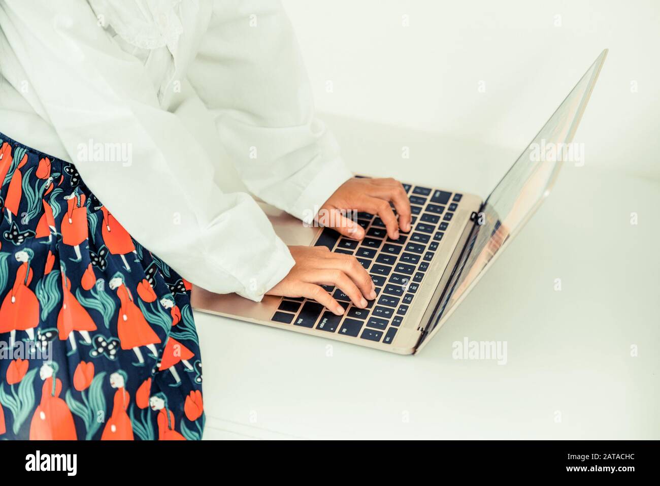 Little kid using laptop computer sitting on white background. Close up ...
