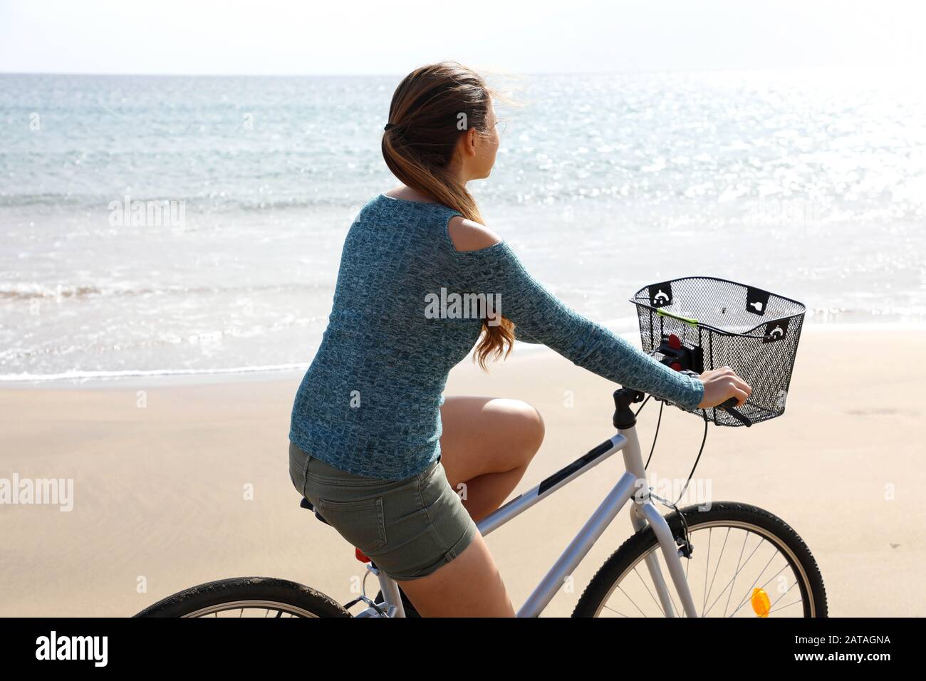 Back view portrait of young woman riding on bicycle enjoying sun on the ...