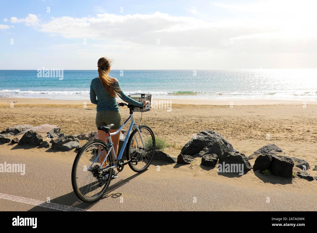 Back view female biker enjoying view of the Atlantic Ocean in Playa ...