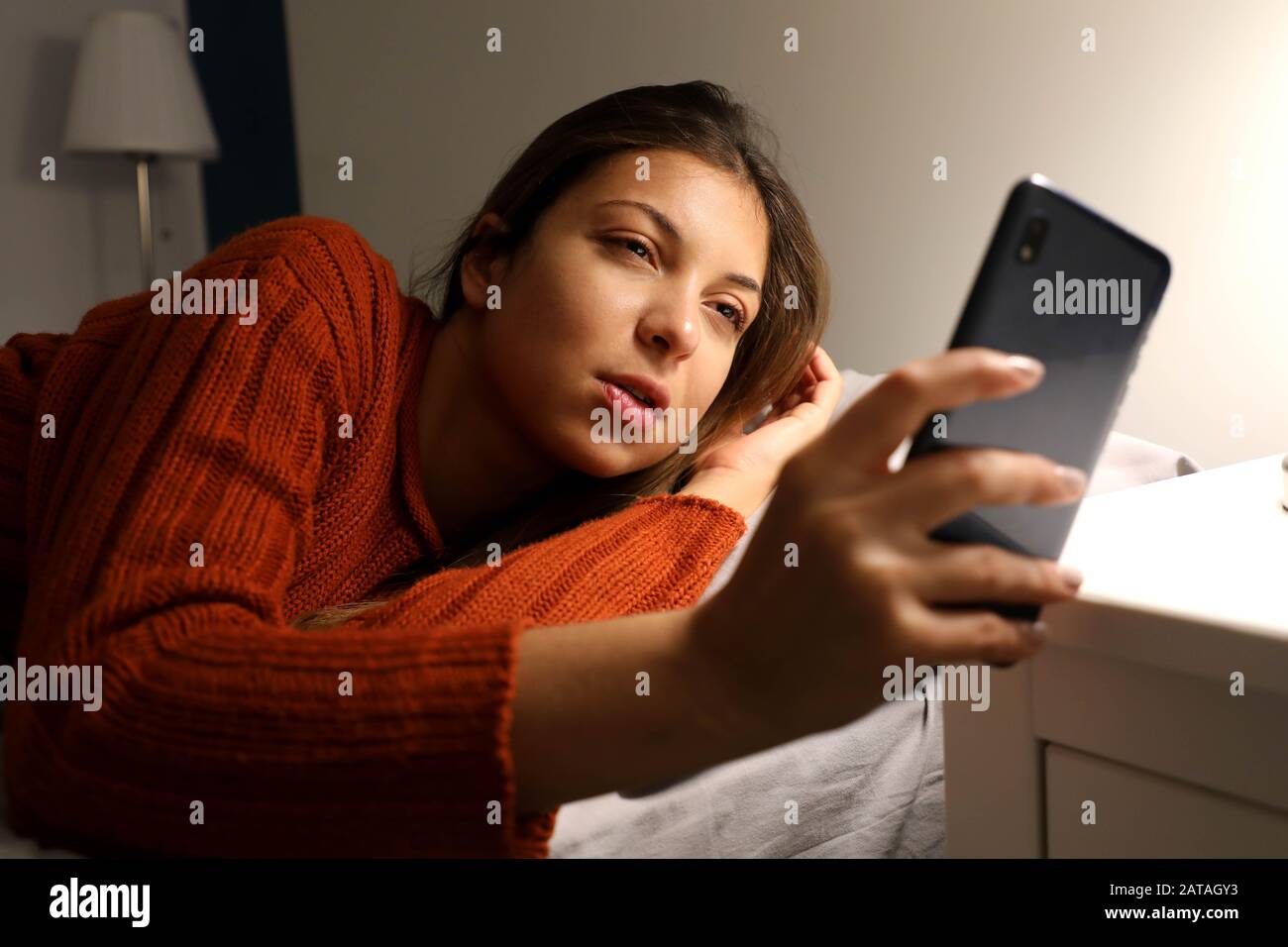 Girl suffering insomnia checks the time on the phone. Young woman awake ...
