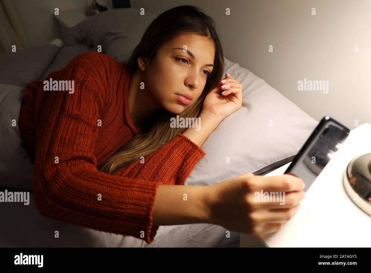 Girl suffering insomnia checks the time on the phone. Young woman awake ...