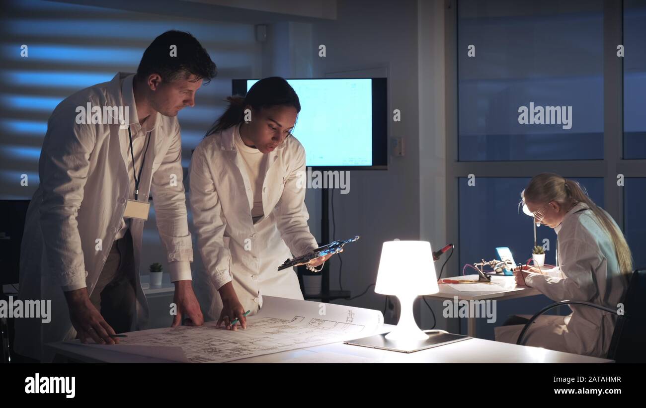 Man and woman in lab coats working in electronics lab with motherboard ...