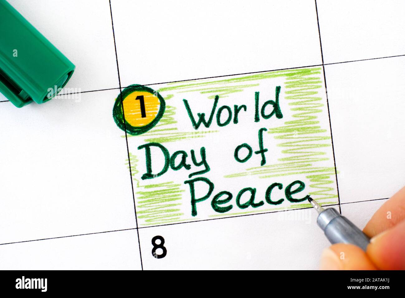 Woman fingers with green pen writing reminder World Day of Peace in ...