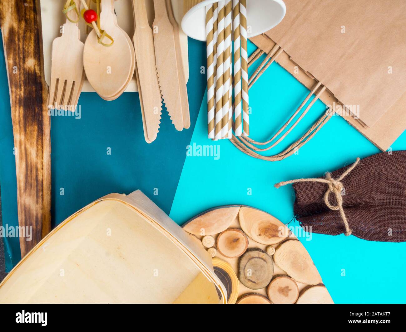 Disposable wooden cutlery and paper bag on trendy blue color background ...