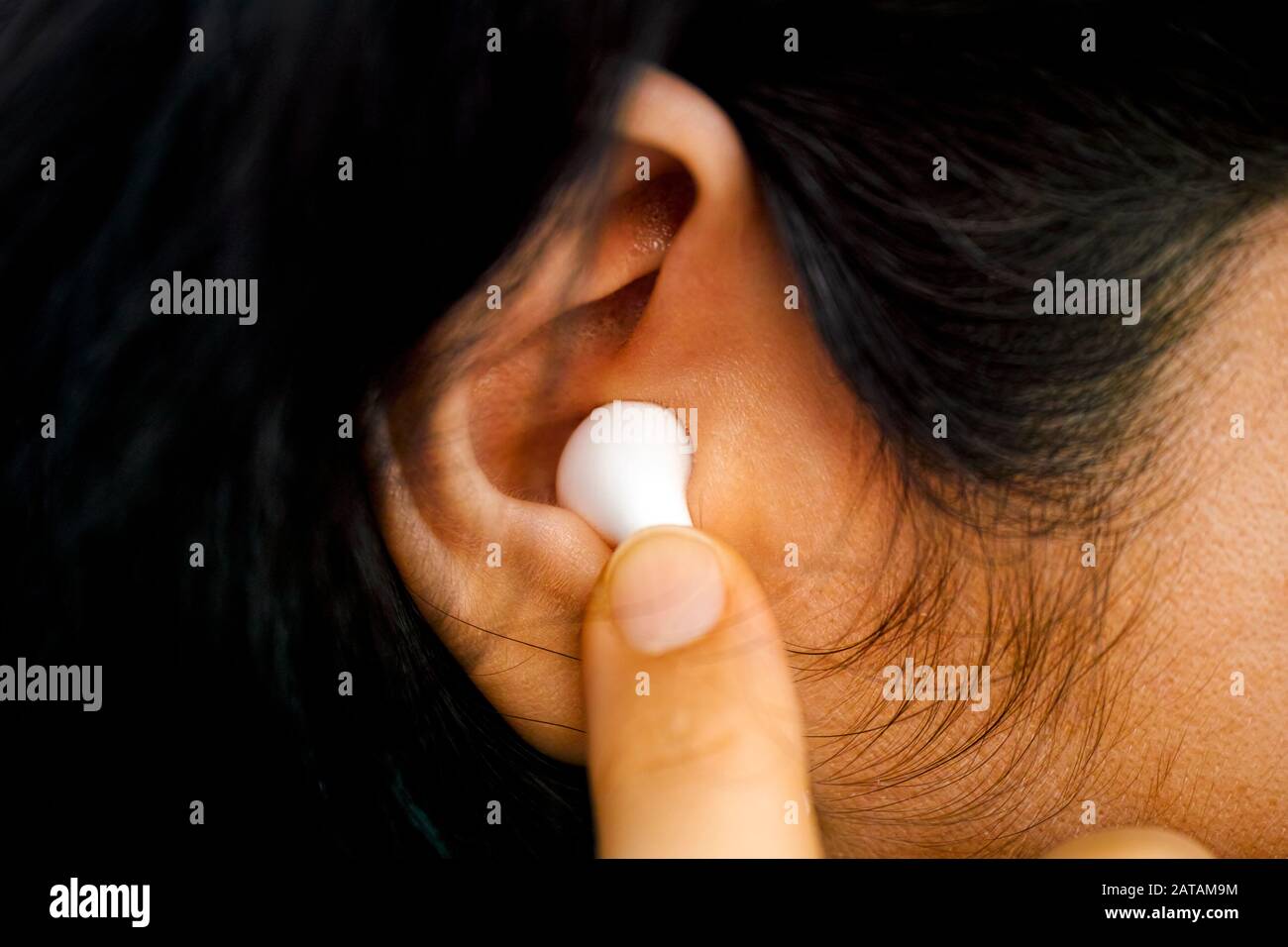 Close-up of wireless earbud in woman ear with her finger Stock Photo ...