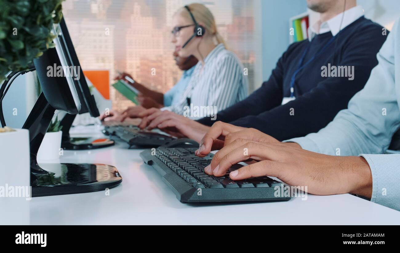 Medium shot of operators hands typing on keyboard in modern office ...