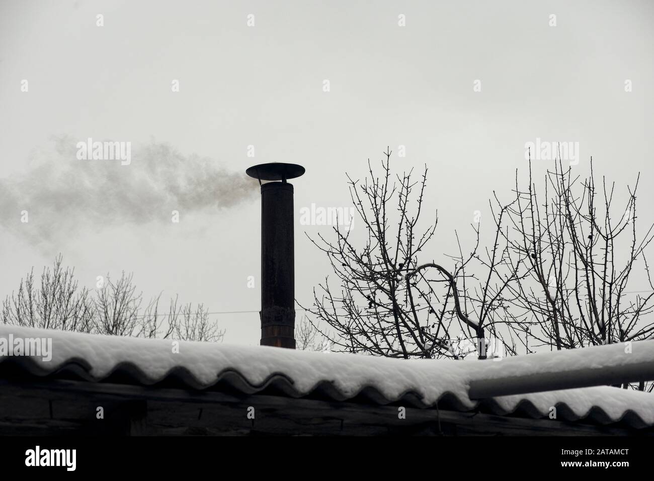 Chimney on roof with smoke coming out. Winter time Stock Photo - Alamy
