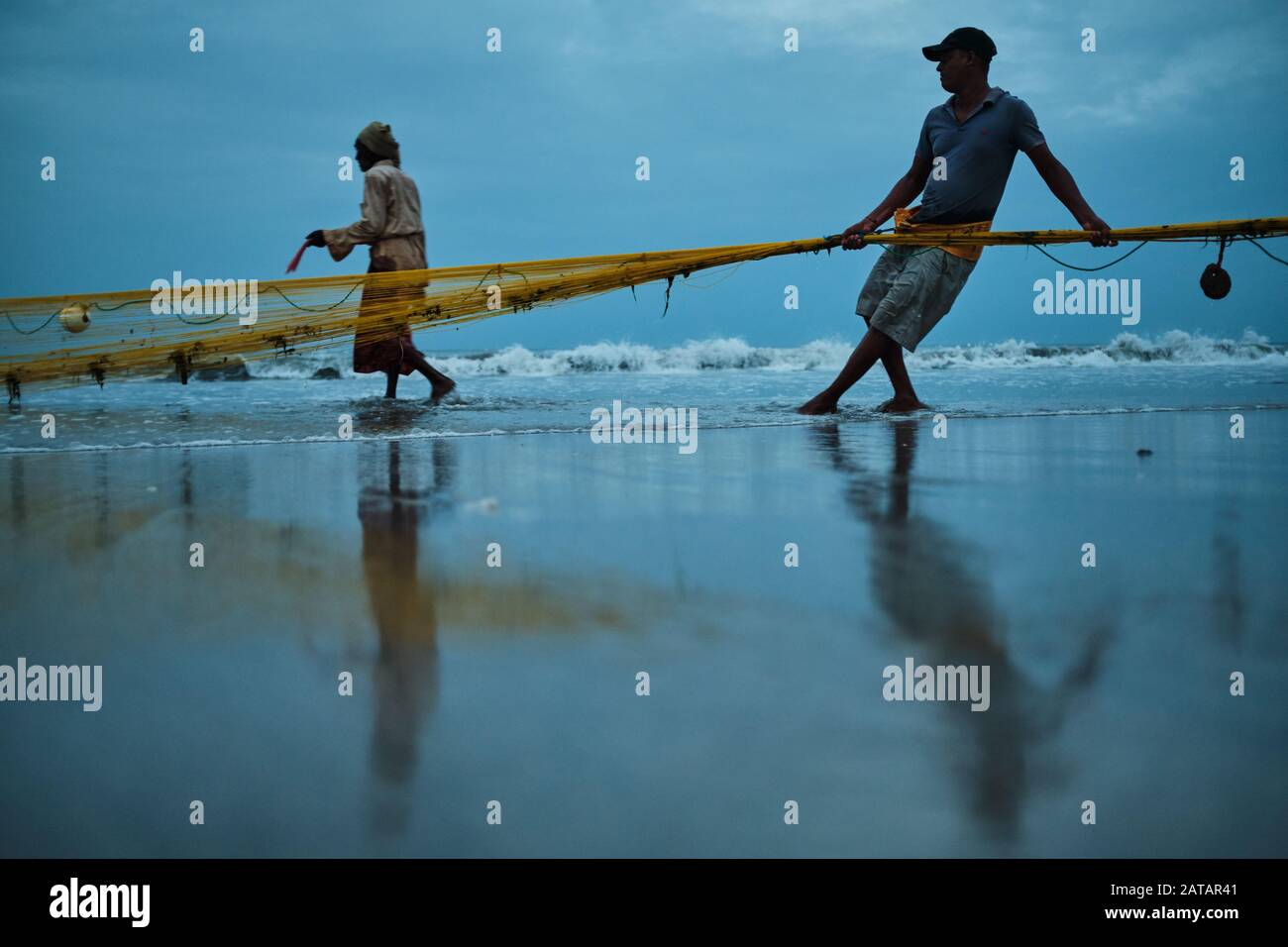 Two fishermen pulling the nets out of the ocean on the beach in Sri ...