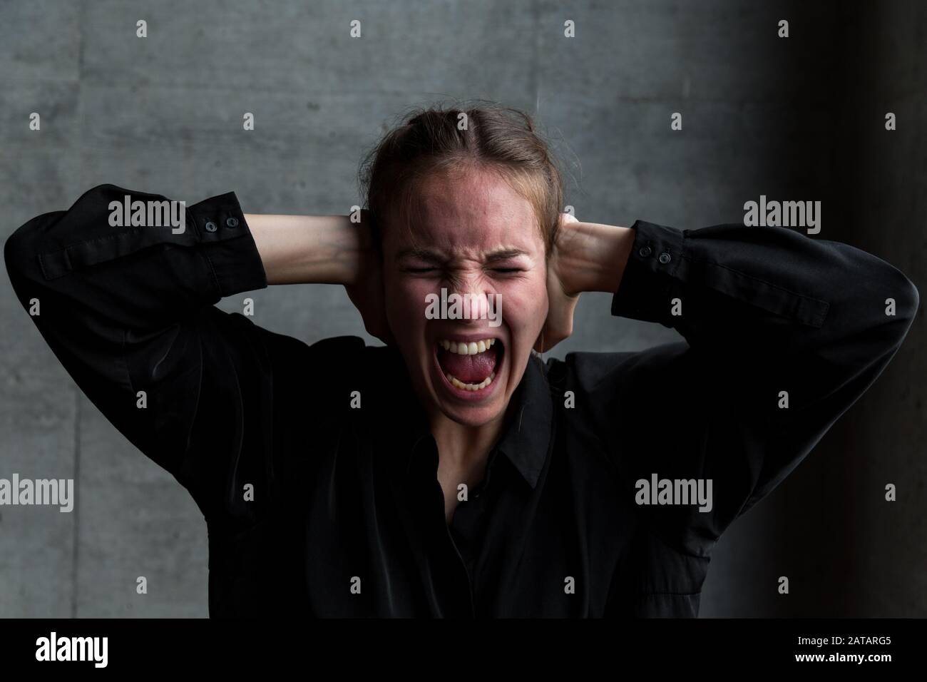 Young Woman Screaming in Agony with Hands Covering Ears Stock Photo - Alamy