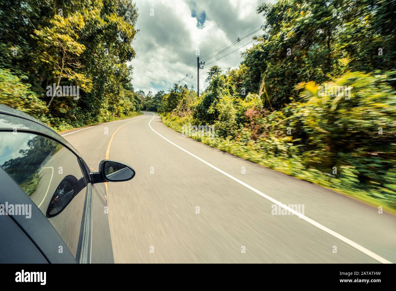 Side view of black car driving on road in forest highway in summer ...