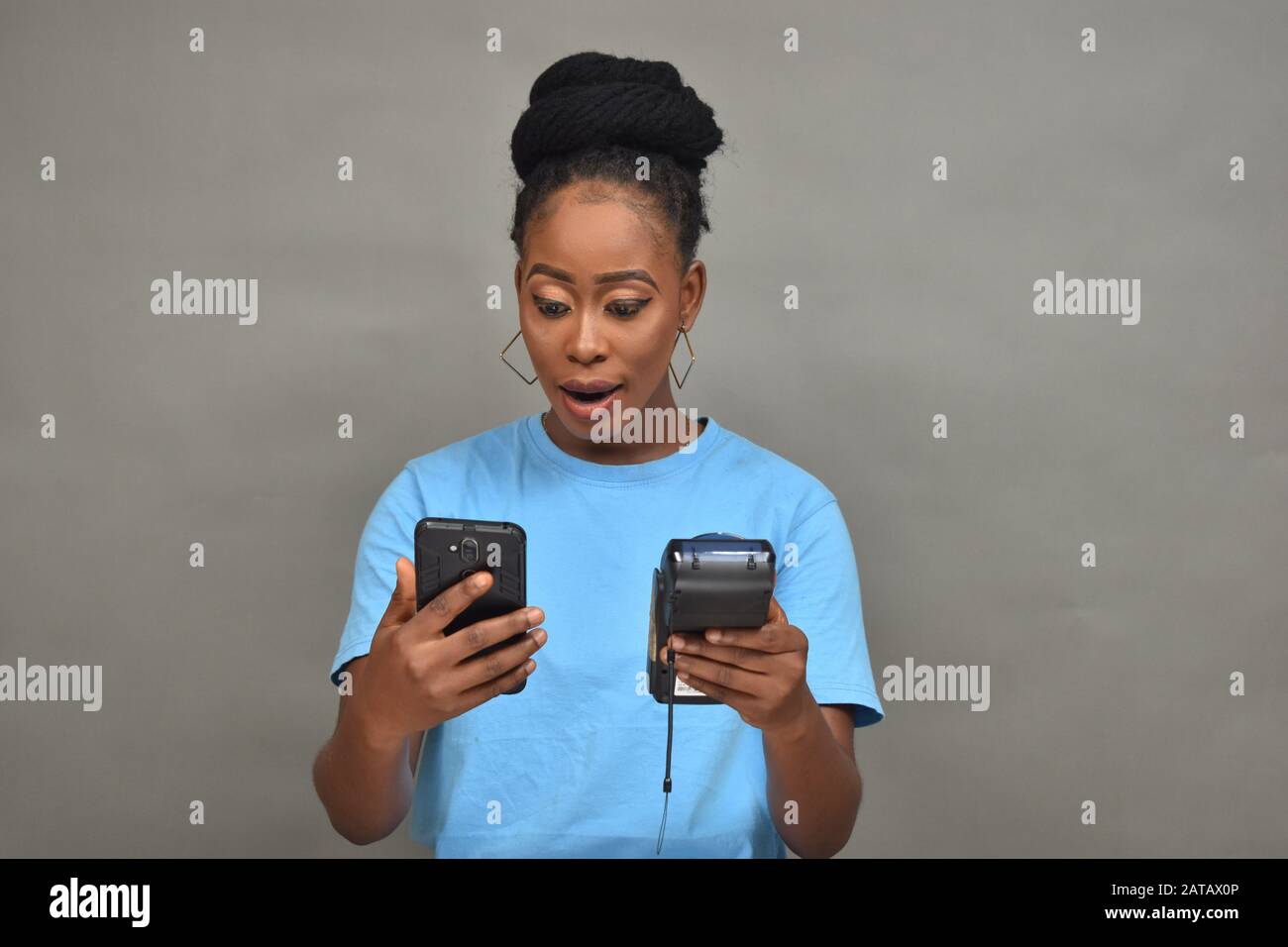 pretty young black woman holding a phone and pos device feeling excited ...