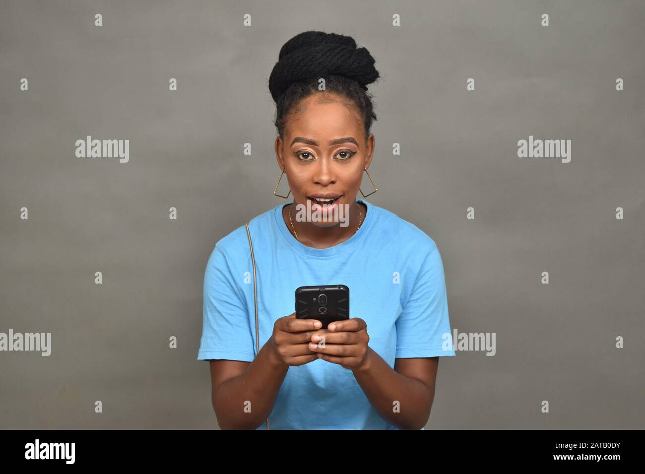 beautiful young african lady holding her mobile phone, looking ...