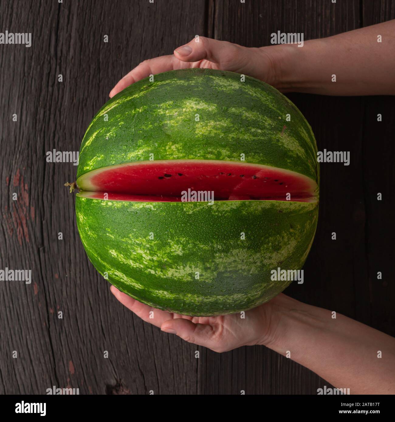 Ripe watermelon in female hands. Top view, rustic style. juicy pulp ...
