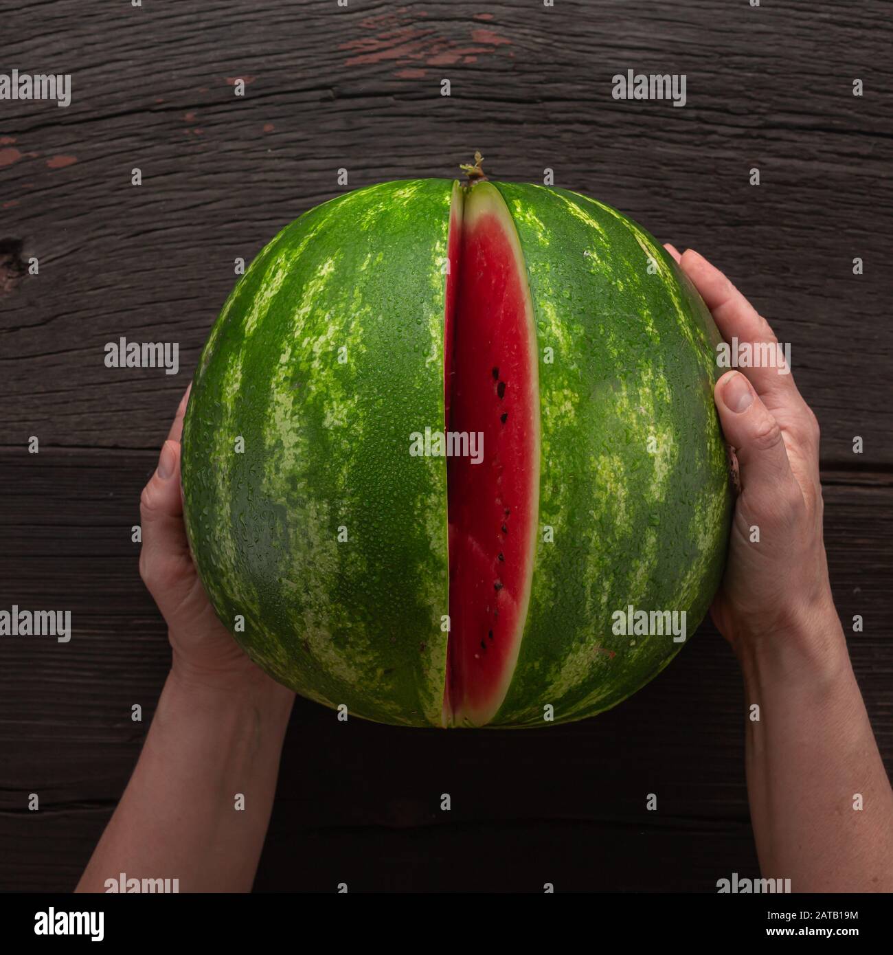Ripe watermelon in female hands. Top view, rustic style. juicy pulp ...