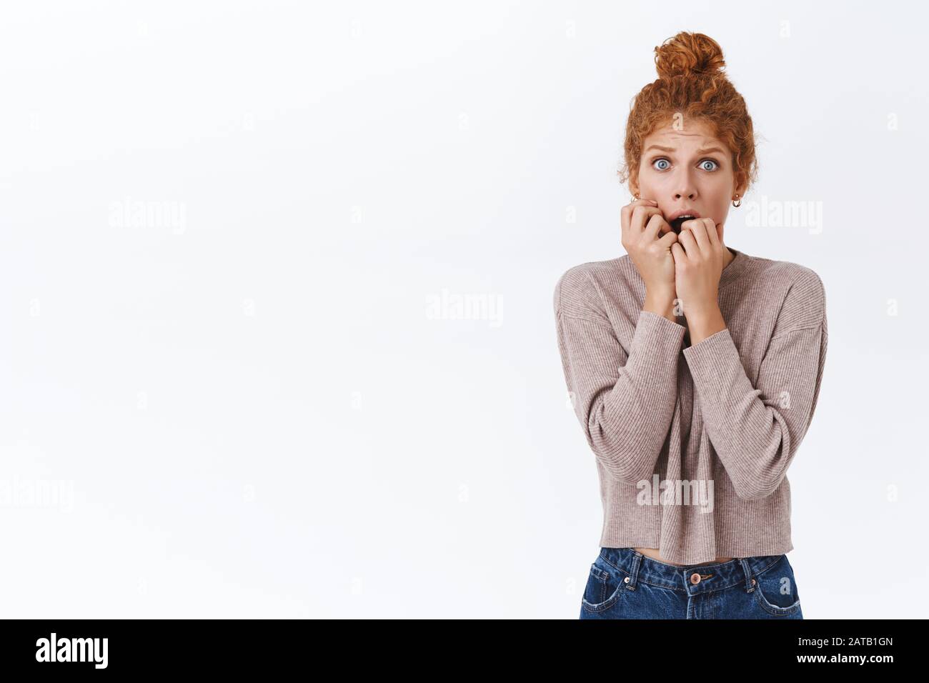 Scared, worried shocked redhead woman with curly hair in messy bun ...
