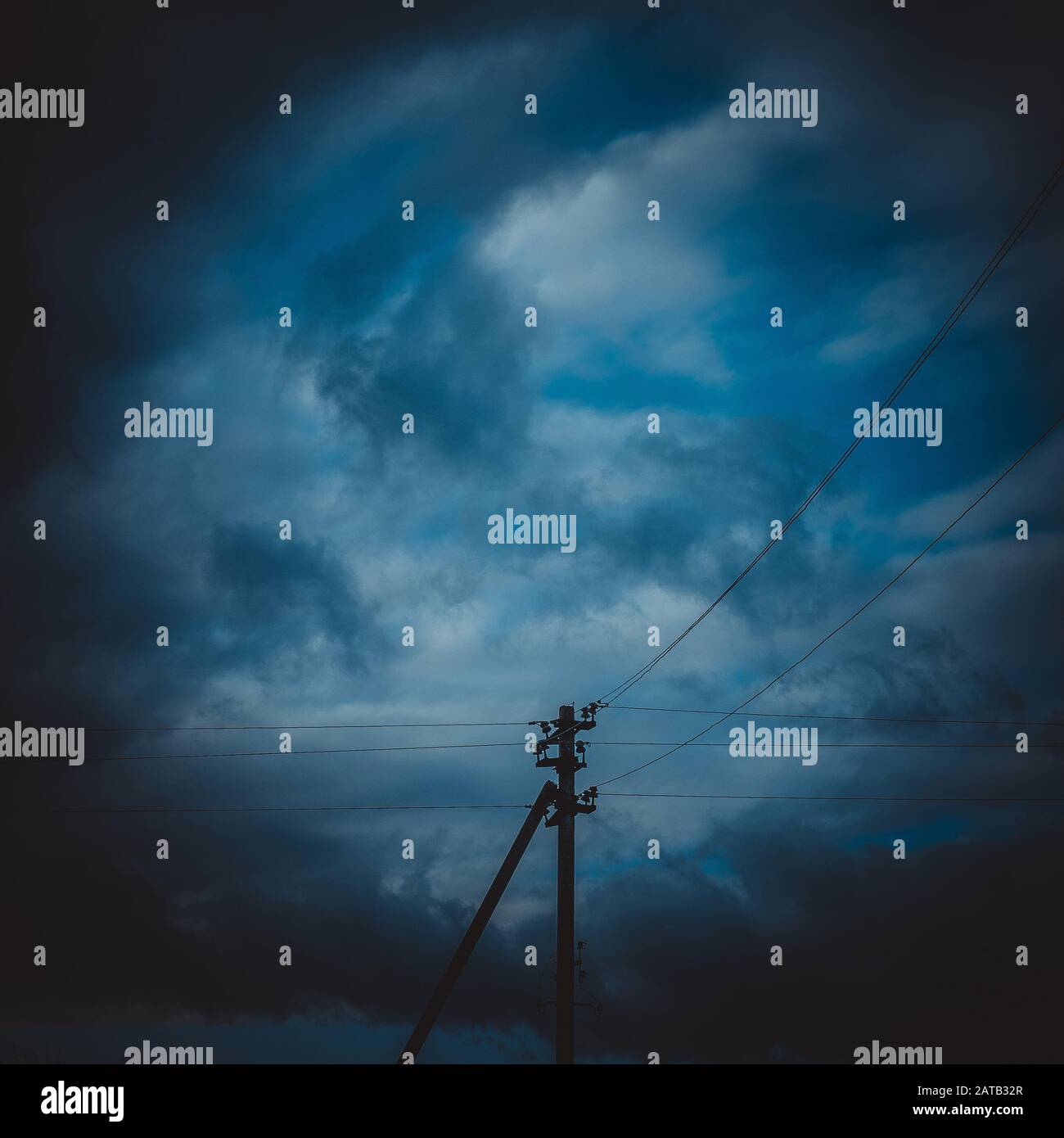 Electric pole. The wires are in the form of a triangle. Cloudy sky ...