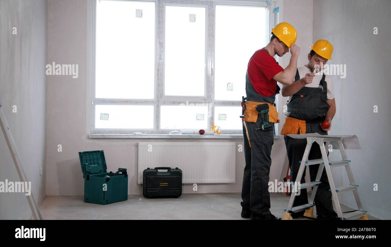 Apartment repair - two men workers discussing an apartment plan Stock ...