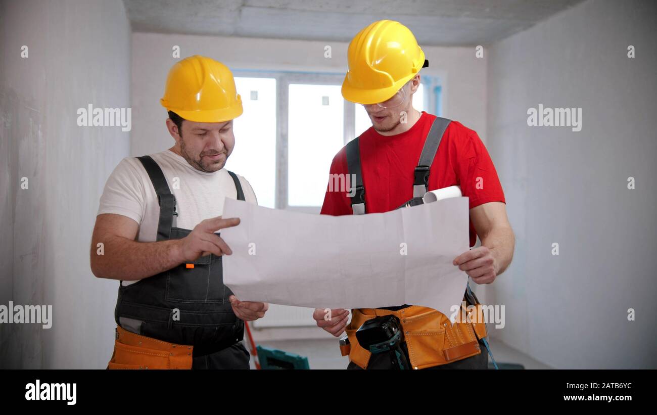 Apartment repair - two men workers discussing layout Stock Photo - Alamy